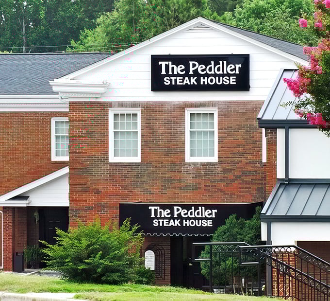 The brick exterior of The Peddler Steak House stands like a humble guardian of beef excellence, promising carnivorous delights within its unassuming walls.