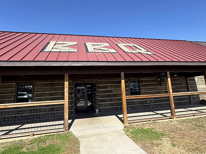 The rustic log cabin exterior of JD's Smokehouse promises authentic barbecue treasures within. That red roof? Nature's way of saying "good food ahead."