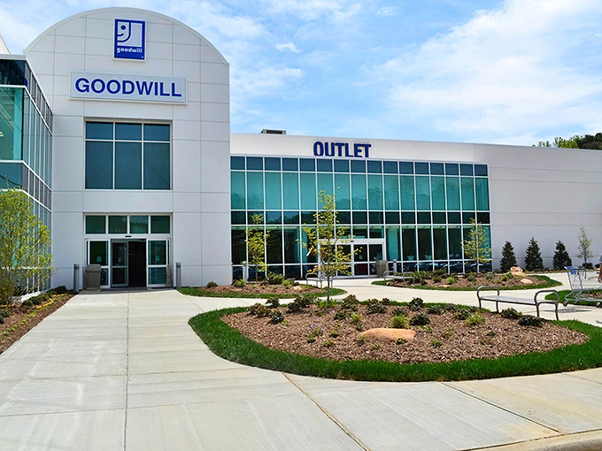 The modern glass facade of Asheville's Goodwill Outlet gleams in the afternoon light, promising treasure hunters a cavernous wonderland of possibilities within.