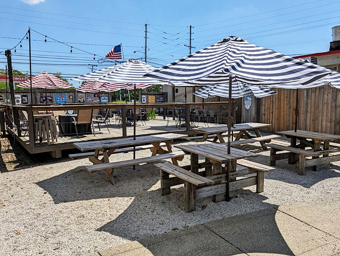 The outdoor patio at The Red Onion offers a perfect summer escape with wooden picnic tables, striped umbrellas, and that essential American flag waving in the Ohio breeze.