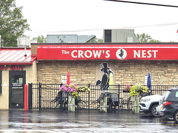 The stone facade and bright red awning of The Crow's Nest stands as a beacon to hungry travelers, even on rainy days when comfort food calls loudest.