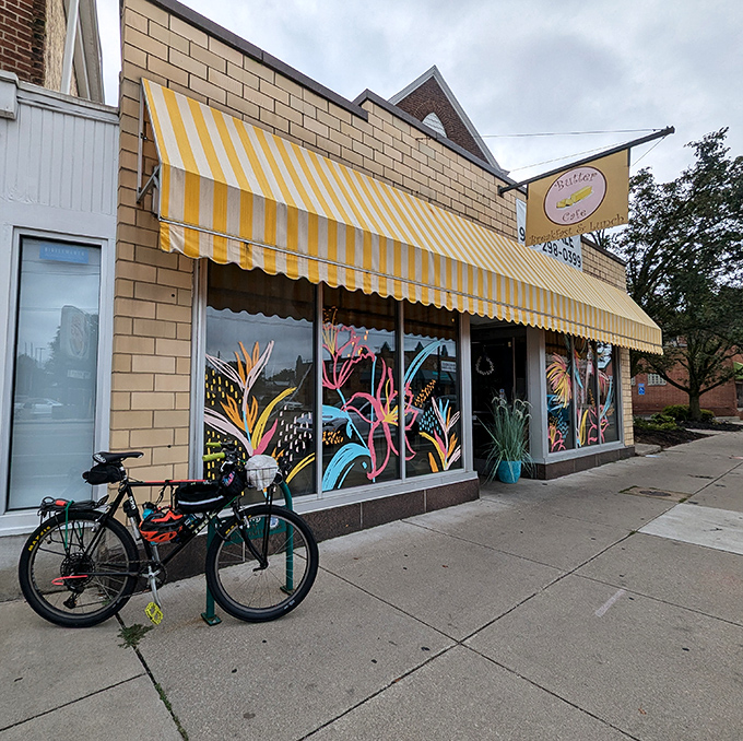 The cheerful yellow-striped awning of Butter Cafe beckons like a breakfast lighthouse, promising delicious refuge from ordinary morning meals.