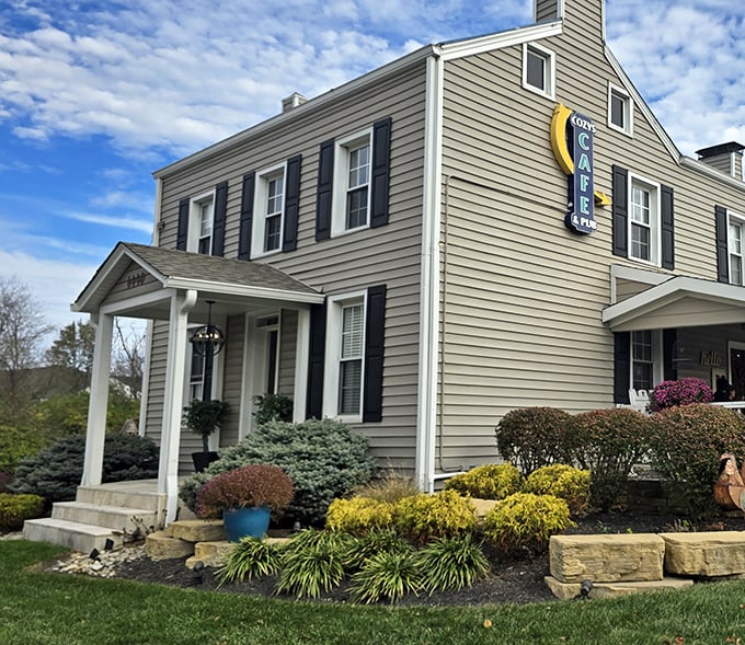 The charming farmhouse exterior of Cozy's Caf&eacute; & Pub stands as a beacon of culinary promise against Ohio's ever-changing skies.