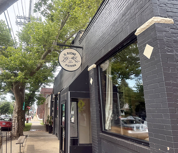 The sleek black exterior of Il Rione might be understated, but that circular sign promises pizza magic within Cleveland's Ohio City neighborhood.