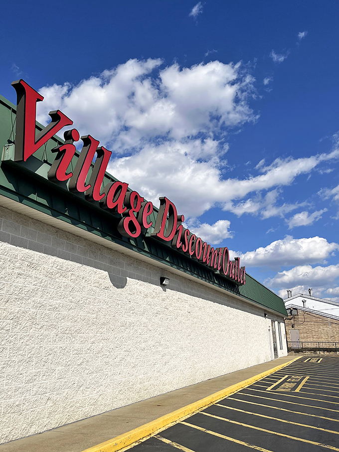 The iconic red cursive sign of Village Discount Outlet stands against an Ohio blue sky, promising treasure hunters a paradise of possibilities within.