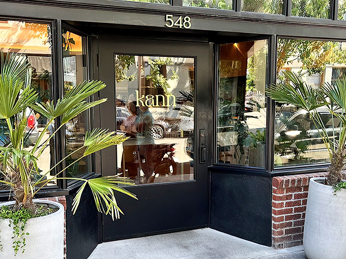 Kann's sleek exterior beckons with tropical palm sentinels standing guard. The modern black fa&ccedil;ade with "548" prominently displayed offers a stylish Portland welcome.