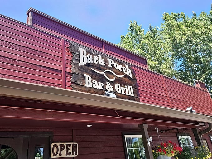 The rustic red exterior of Back Porch Bar & Grill welcomes hungry travelers with its weathered charm and promise of comfort food done right.