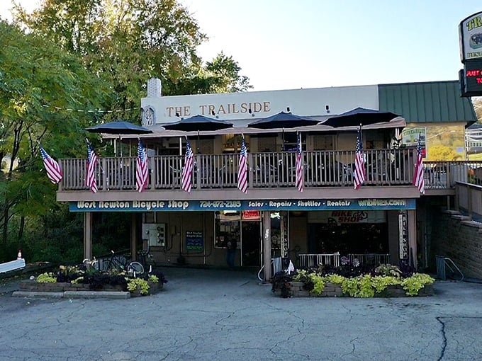 The Trailside's welcoming facade, complete with American flags and outdoor seating, beckons weary travelers like a culinary lighthouse on the Great Allegheny Passage.