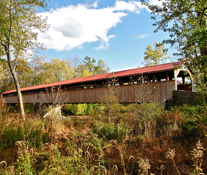 The iconic red roof of Pomeroy-Academia Covered Bridge stands out against Pennsylvania's blue sky like nature's perfect postcard.