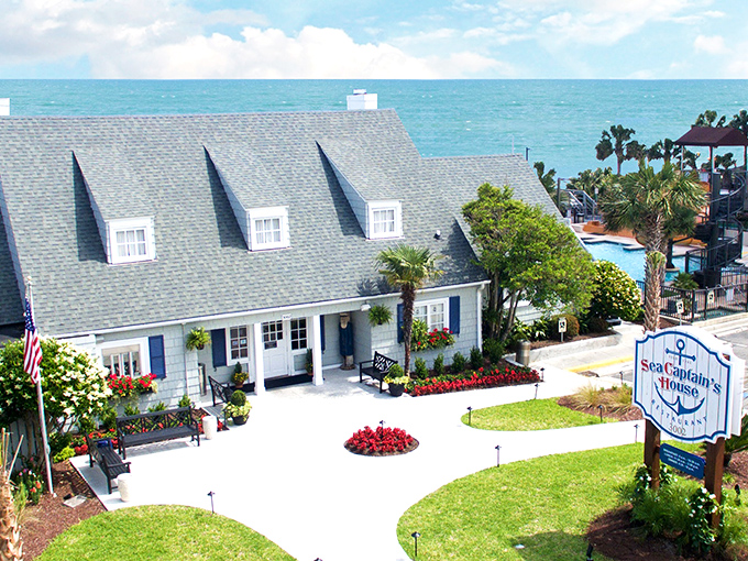The quintessential coastal cottage stands defiant among high-rises, its blue shutters and vibrant flower beds whispering, "Slow down, you're on beach time now."