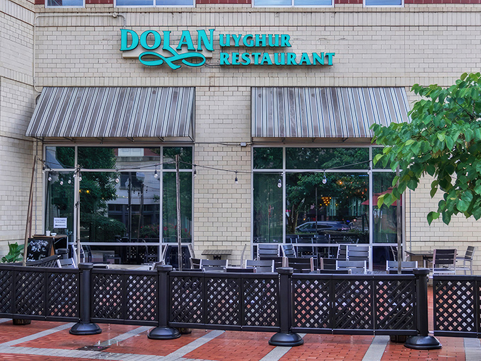 The turquoise sign of Dolan Uyghur Restaurant glows like a beacon against beige brick, promising culinary adventures beyond the modest exterior.