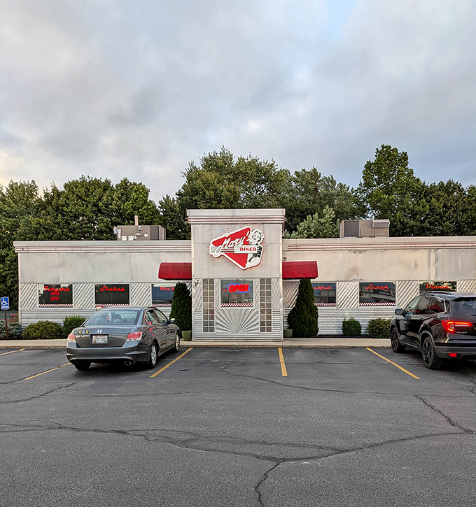 The classic white exterior of Mary's Diner in Geneva beckons like a time machine disguised as a restaurant. Red accents and retro signage promise comfort food paradise.