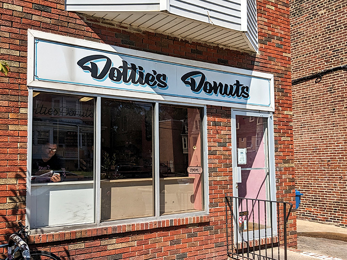 The unassuming brick storefront of Dottie's Donuts in West Philadelphia, where vegan donut magic happens daily behind that simple blue sign.