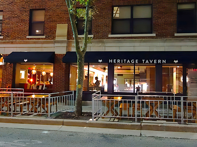 Heritage Tavern's brick fa&ccedil;ade glows with warm invitation as evening falls, its fox logo standing sentinel over Madison's culinary gem.