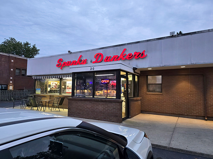 That iconic red neon sign beckons like a lighthouse for the sugar-deprived, glowing with the promise of fried dough perfection just steps away.