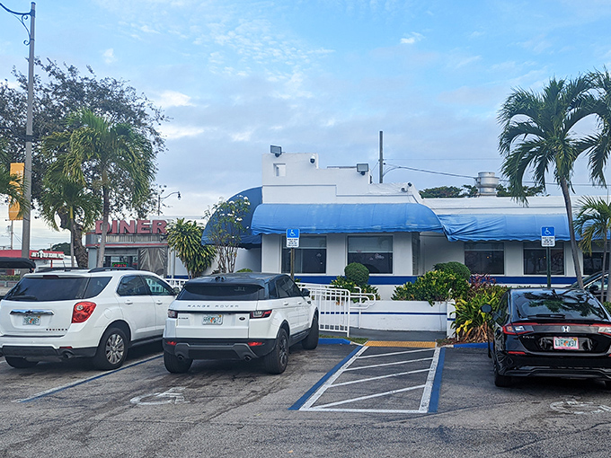 The classic blue awnings and bold red "DINER" sign beckon hungry travelers like a neon lighthouse in a sea of chain restaurants.