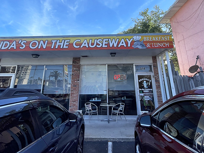 The vibrant orange storefront of Brenda's On the Causeway stands like a sunrise beacon for hungry travelers along Dunedin's waterfront.