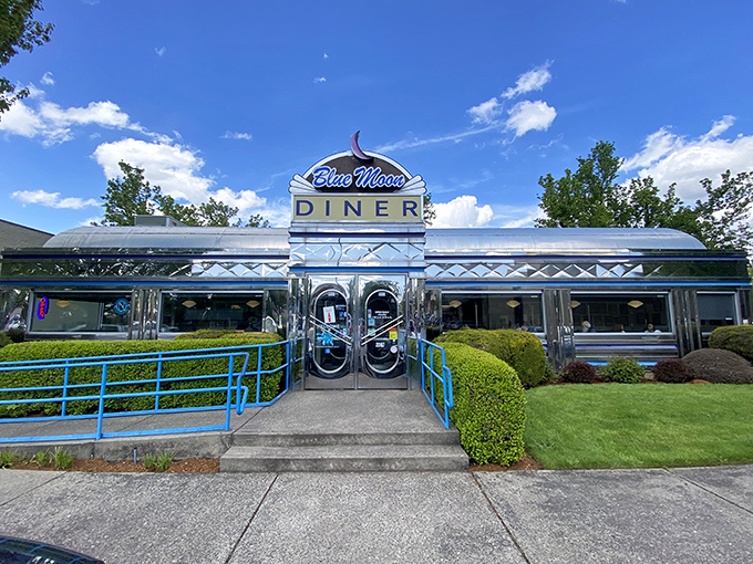 The iconic Blue Moon Diner sign shines like a beacon for hungry travelers, promising classic American comfort in its gleaming chrome exterior.