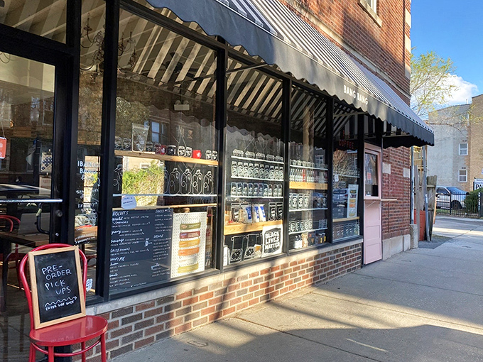 The sidewalk view offers a tantalizing glimpse of what awaits inside: those vibrant red chairs practically screaming, "Sit here and eat something delicious!"