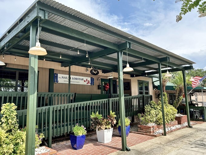 The welcoming covered porch at The Nauti Lobstah beckons like a lighthouse to seafood lovers, complete with colorful planters that add a touch of coastal charm.