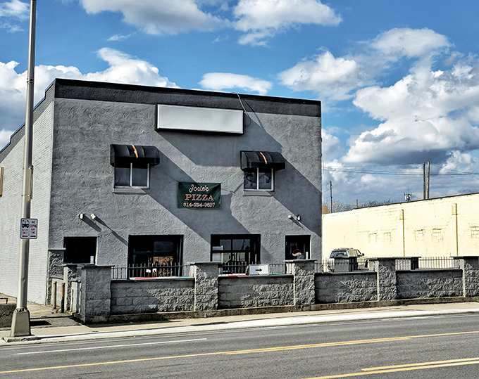 The gray fortress of flavor stands proudly on West Broad Street, its red umbrellas beckoning like culinary lighthouses to pizza pilgrims.
