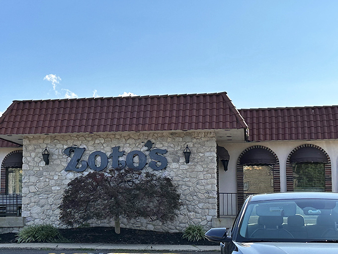 The stone facade and burgundy roof of Zoto's Diner stands like a culinary lighthouse, beckoning hungry travelers with the promise of comfort food excellence.