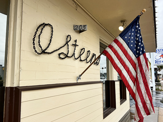 The American flag waves a patriotic hello outside O'Steen's, where the simple script signage promises authentic coastal dining without pretension.