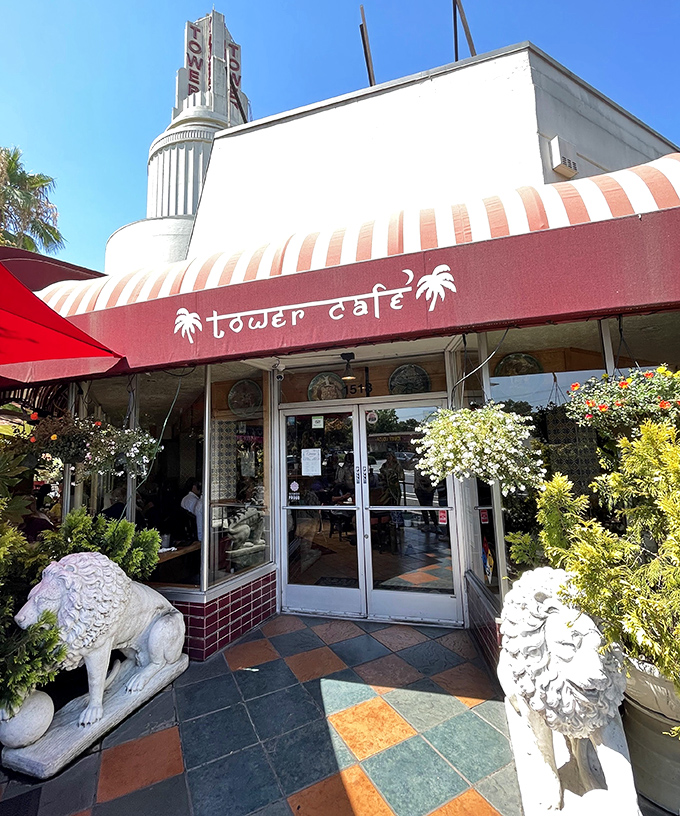 The iconic Tower Cafe entrance, where stone lions stand guard and palm tree logos promise a culinary adventure unlike any other in Sacramento.