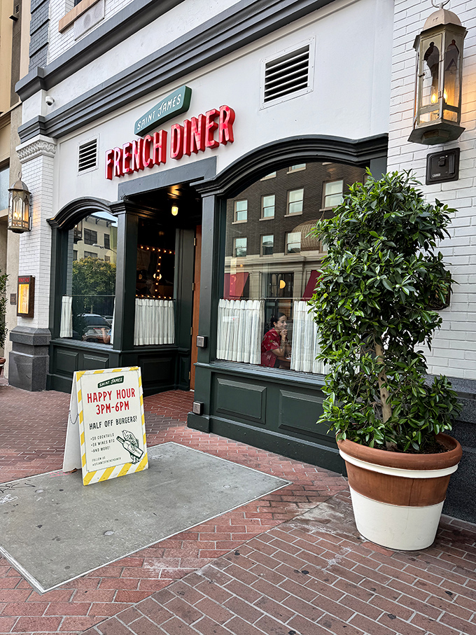 The red neon "FRENCH DINER" sign beckons like a lighthouse for the food-obsessed. Classic white brick, green trim, and that happy hour sign promising half-price burgers&mdash;resistance is futile.