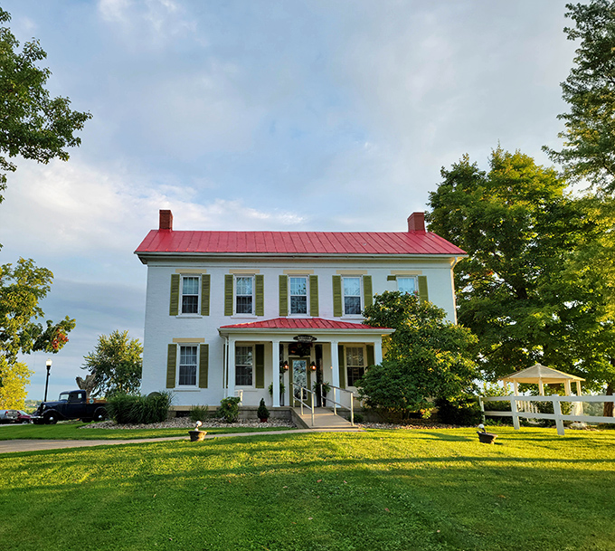 The classic white farmhouse with its striking red roof stands like a culinary lighthouse, beckoning hungry travelers to the rolling hills of Adena.