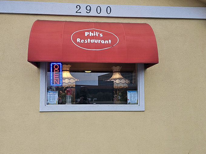 The iconic red awning of Phil's Restaurant beckons hungry travelers like a culinary lighthouse on Central Avenue in Hot Springs.