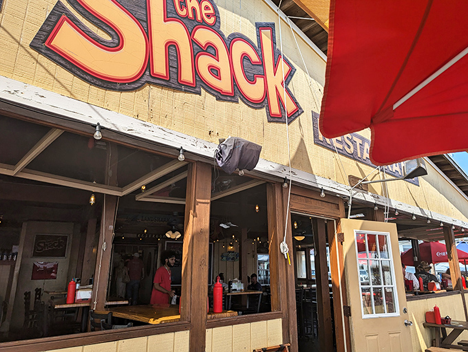 The weathered wooden exterior of The Shack beckons with its no-nonsense charm. Those red awnings aren't just for show—they're signaling "serious seafood ahead."