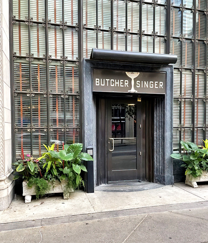 The entrance to Butcher and Singer stands like a portal to another era, where the martini glass logo promises sophisticated pleasures within.