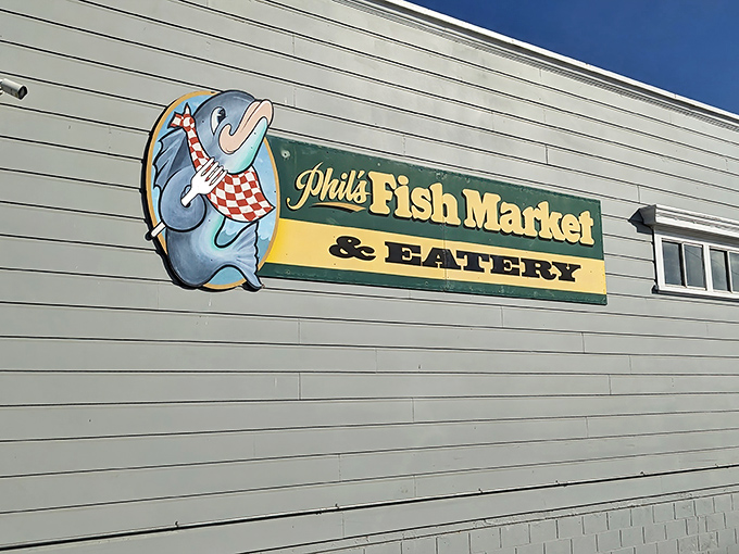 The playful fish-with-a-fork sign at Phil's Fish Market hints at the seafood magic inside, where this humble spot serves treasures far beyond its unassuming walls.