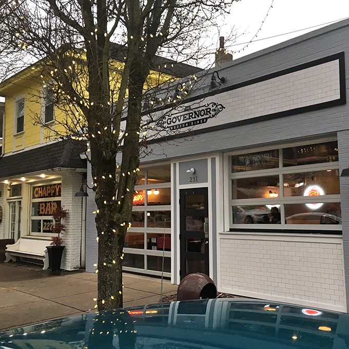 The Governor's crisp white exterior glows with promise at dusk, a beacon of culinary delight nestled between neighborhood establishments.