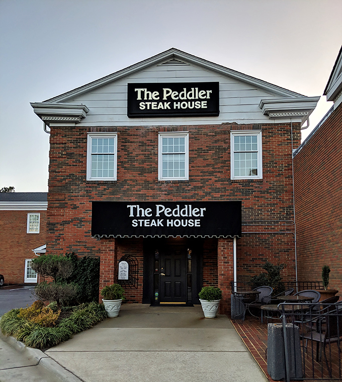 The brick exterior of The Peddler Steak House stands like a humble guardian of beef excellence, promising carnivorous delights within its unassuming walls.