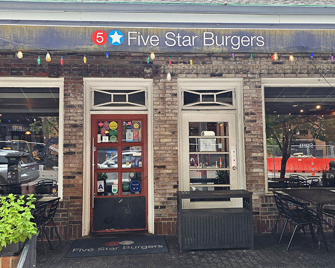 The charming brick exterior of 5 Star Burgers beckons with colorful string lights and lush greenery, like a burger oasis in Clayton's urban landscape.