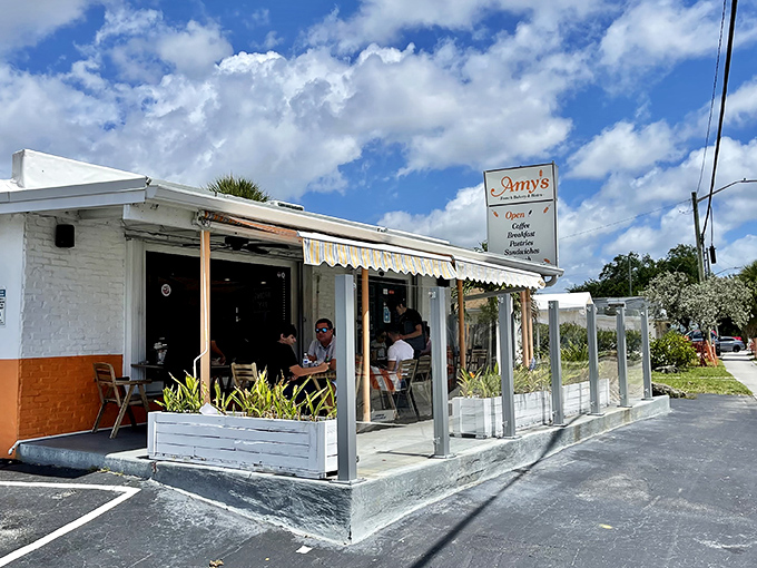 A splash of orange and white with a colorful mural welcomes you to this unassuming French oasis in Pompano Beach.