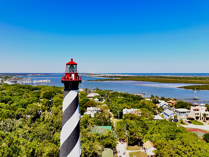 The iconic black and white spiral of St. Augustine Lighthouse stands tall against a perfect Florida sky, like a maritime barber pole guiding ships home.