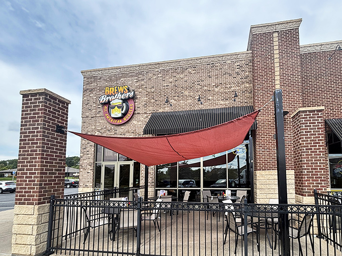 A red sail provides shade for the outdoor patio, where conversations flow as freely as the craft beers waiting just beyond those glass doors.