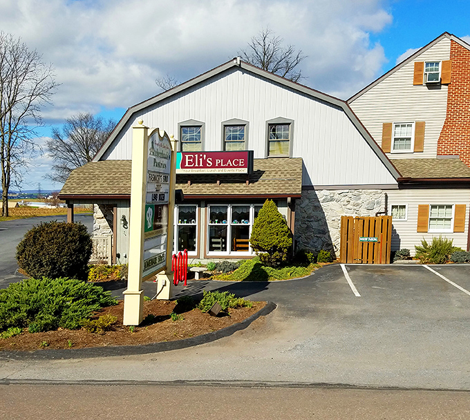 The welcoming facade of Achenbach's, where vibrant marigolds and hanging baskets frame a bakery that's earned its "favorite" status through decades of pastry perfection.