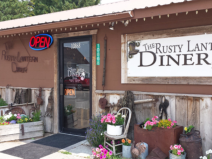 The unassuming exterior of The Rusty Lantern Diner, where colorful flower planters and rustic charm hint at the culinary treasures waiting inside.