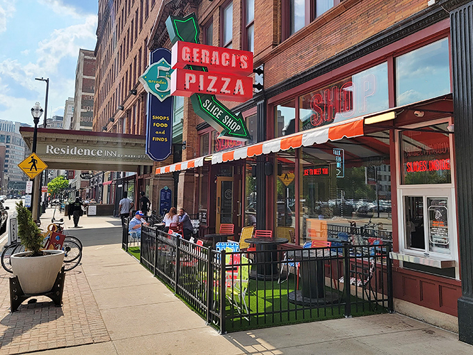 The neon beacon of Geraci's Slice Shop glows like a pizza lighthouse on Cleveland's bustling street, promising salvation for the hungry downtown wanderer.