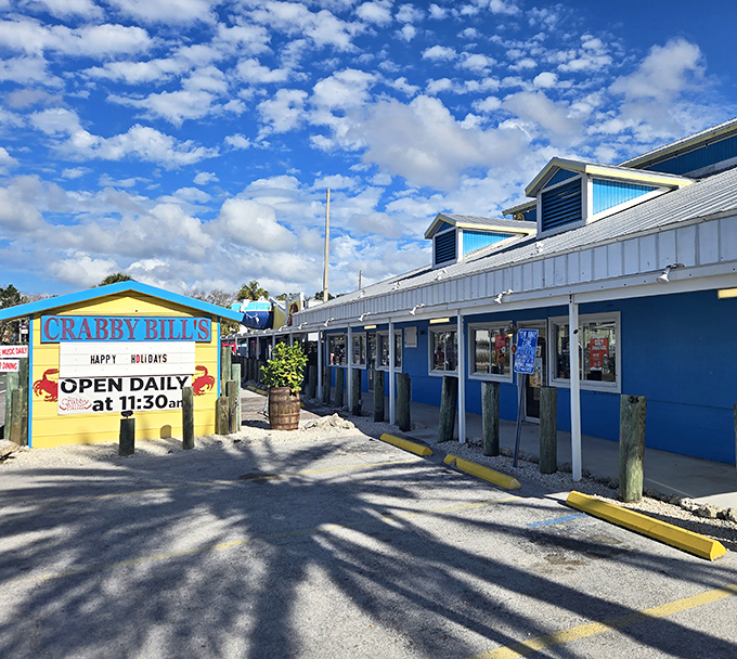 The iconic blue and yellow exterior of Crabby Bill's stands like a cheerful sentinel against Florida's perfect sky, promising seafood treasures within.