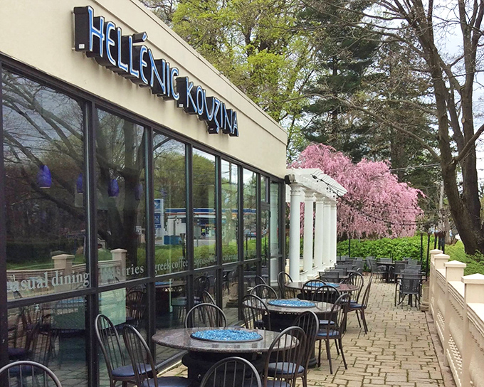 The blue sign of Hellenic Kouzina glows like a Mediterranean beacon against Pennsylvania skies, promising authentic Greek flavors just steps from the charming outdoor patio.