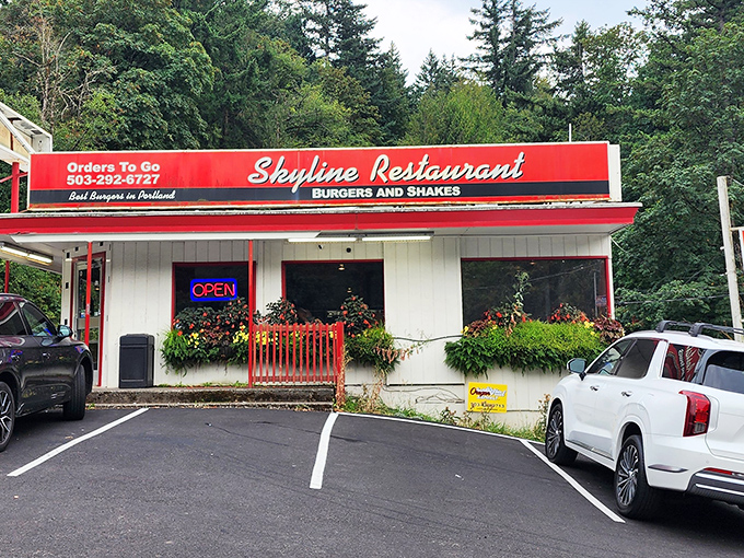 The classic red and white exterior of Skyline Restaurant stands like a time capsule among towering Douglas firs, promising burger nirvana to all who enter.