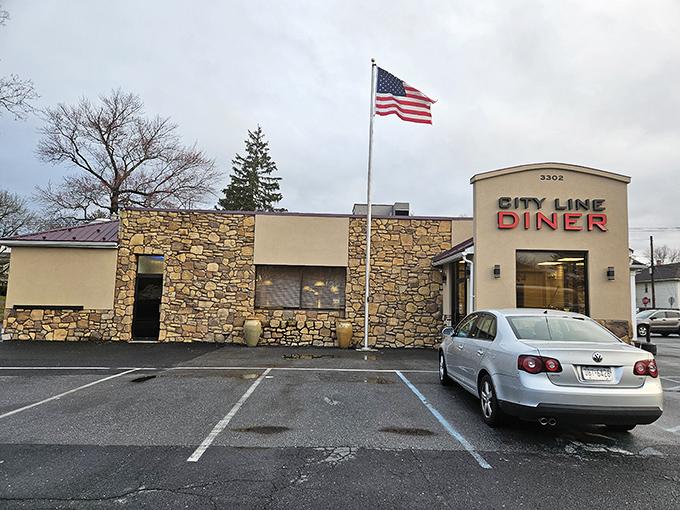 The stone facade of City Line Diner stands proudly under Pennsylvania skies, an American flag waving as if to signal "deliciousness ahead!"