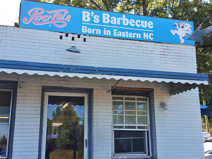 The blue sign says it all: "Born in Eastern NC." No website, no fancy marketing&mdash;just a white brick building that's become a barbecue pilgrimage site.