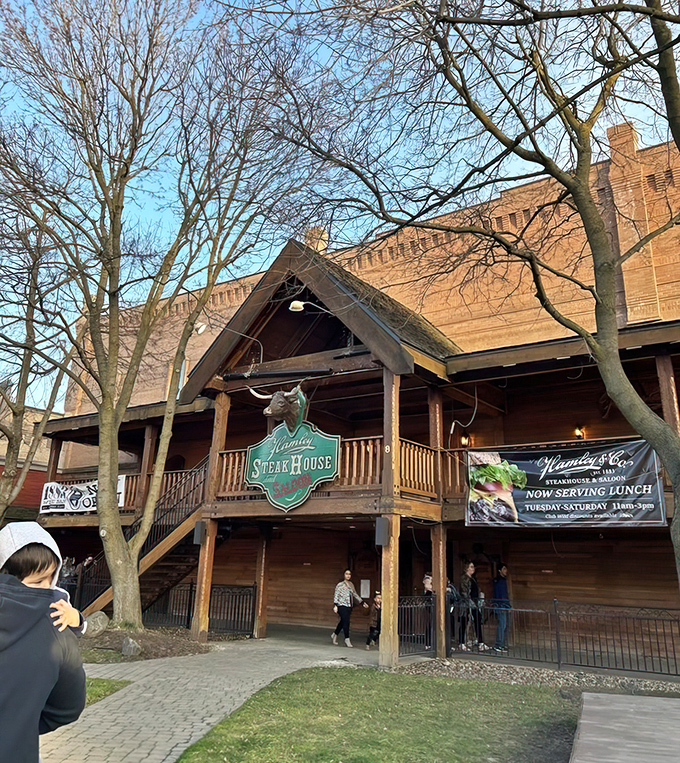 Winter's bare branches frame this Western treasure, where the promise of sizzling steaks and frontier hospitality waits just beyond those wooden steps.