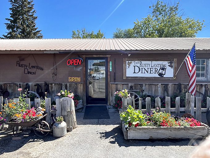 A classic American flag proudly waves beside the entrance, where vintage farm implements and vibrant blooms create an instantly welcoming atmosphere.